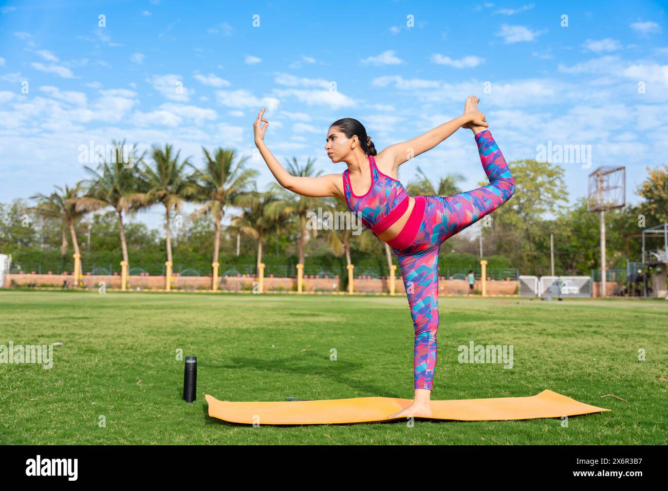 Fit Young indian girl doing dancer, Natarajasana yoga pose in garden ...