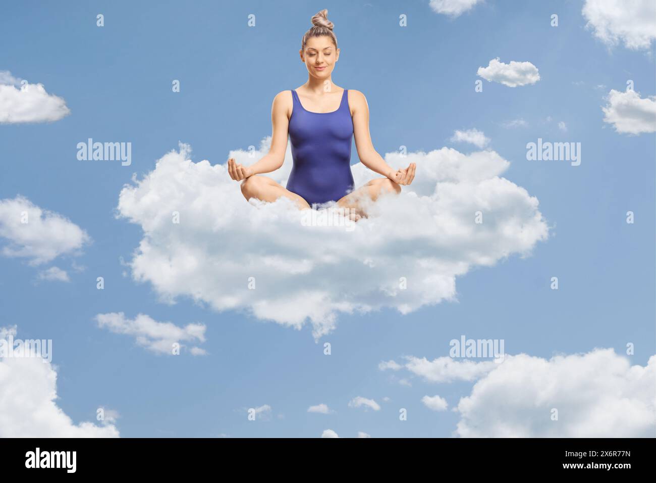 Young woman in a swimming suit sitting on a cloud in a meditation pose ...