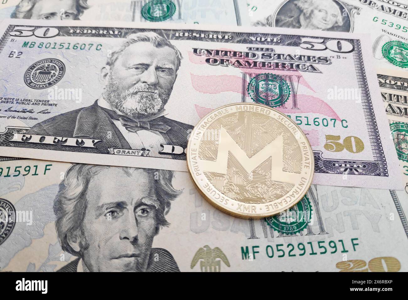 Close-up on a golden Monero coin on top of a stack of US Dollar ...