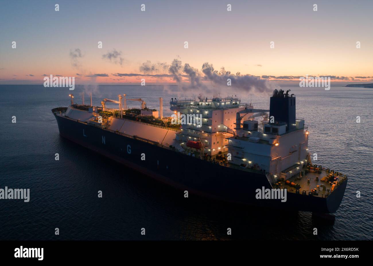 A large LNG tanker docks at an industrial port terminal for cargo ...
