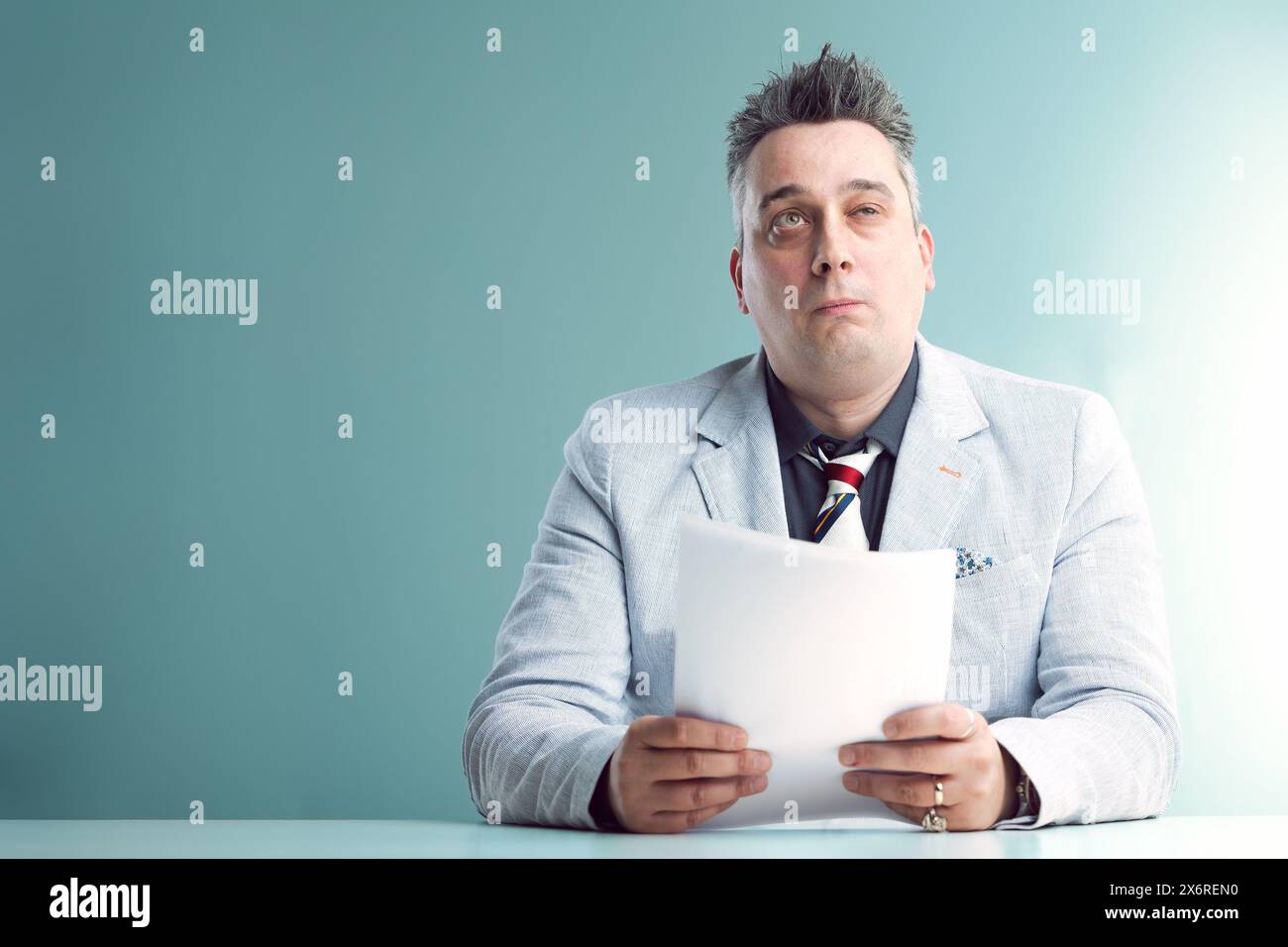 Confused anchorman in grey suit holds documents, his expression ...