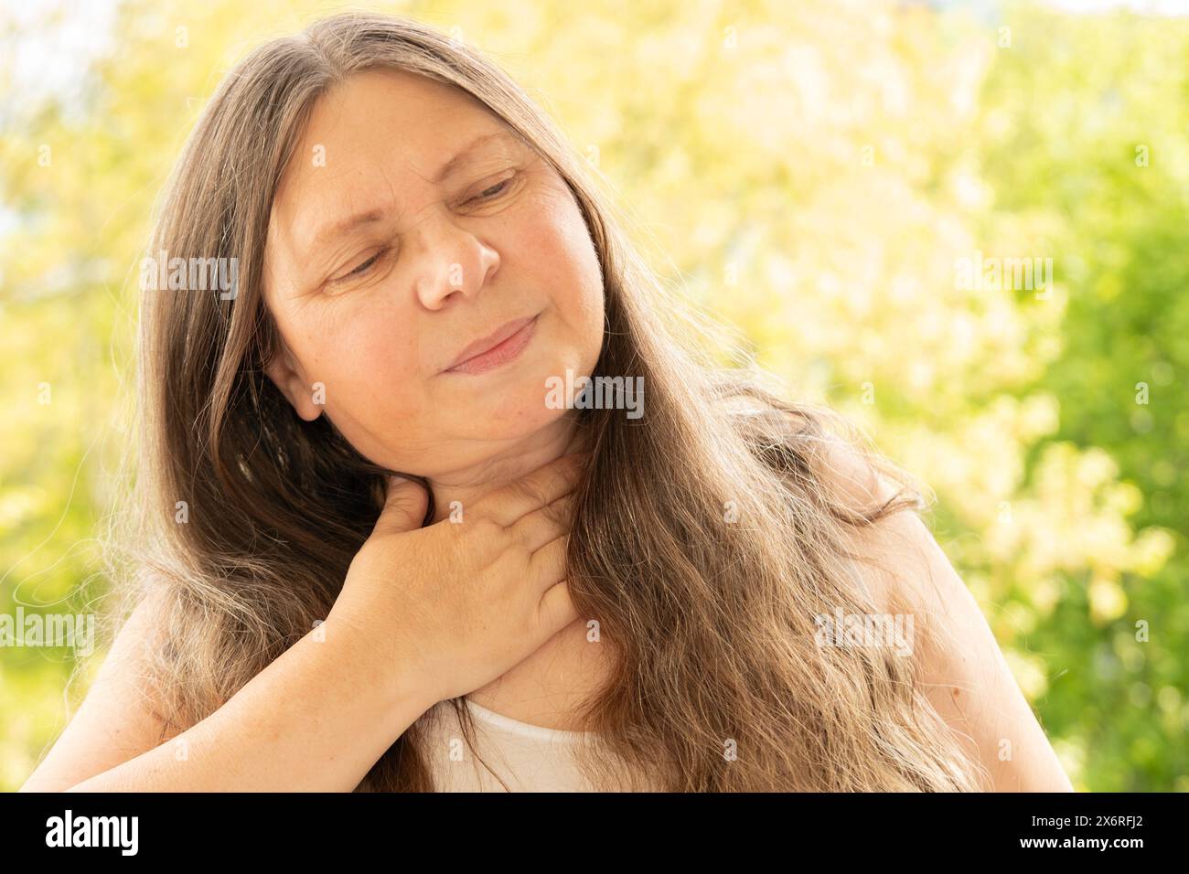 close-up mature female neck, patient holding affected area ...