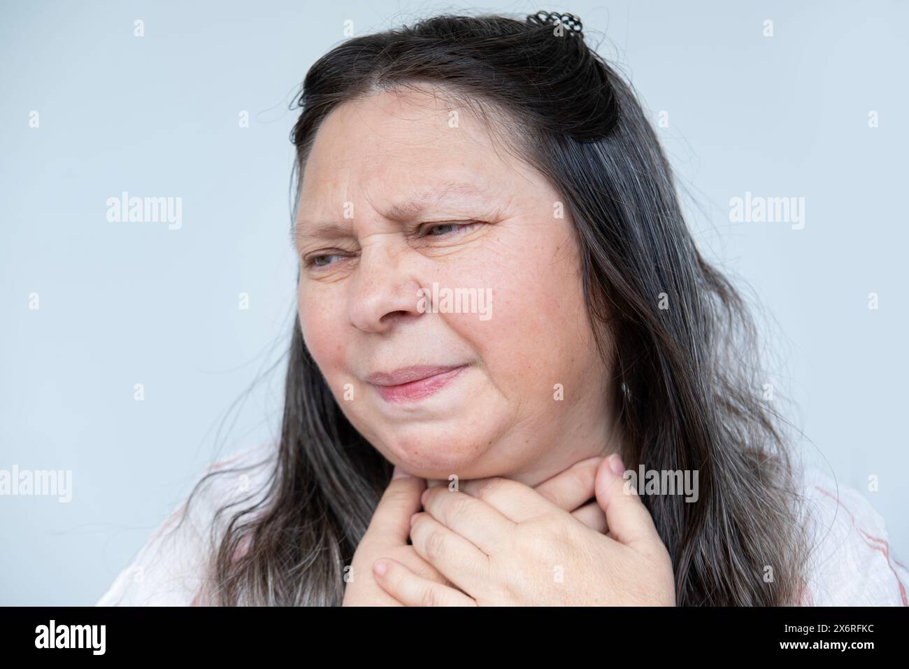 close-up mature female neck, patient holding affected area ...