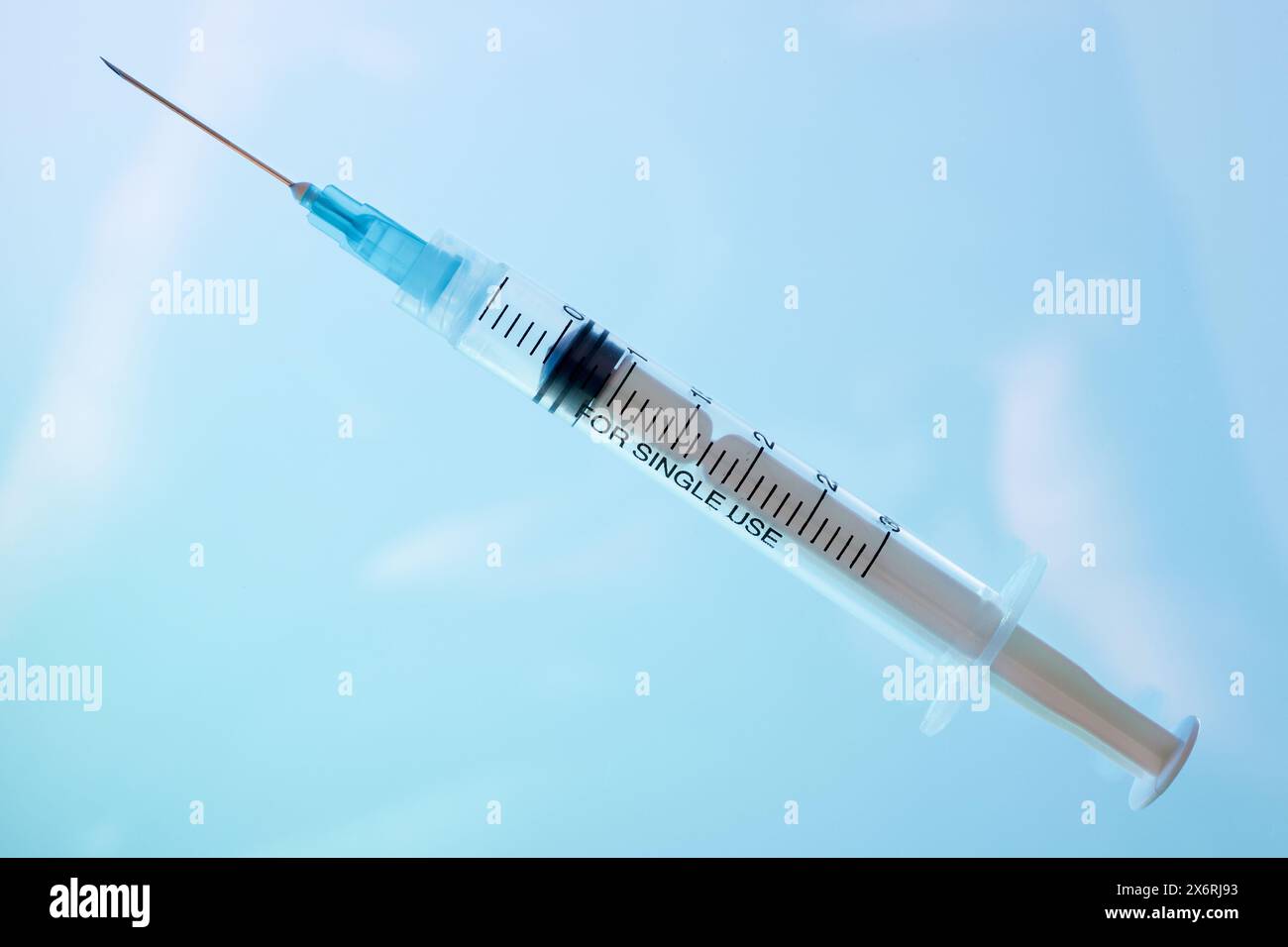 Close up of a hypodermic syringe on a blue surface Stock Photo - Alamy