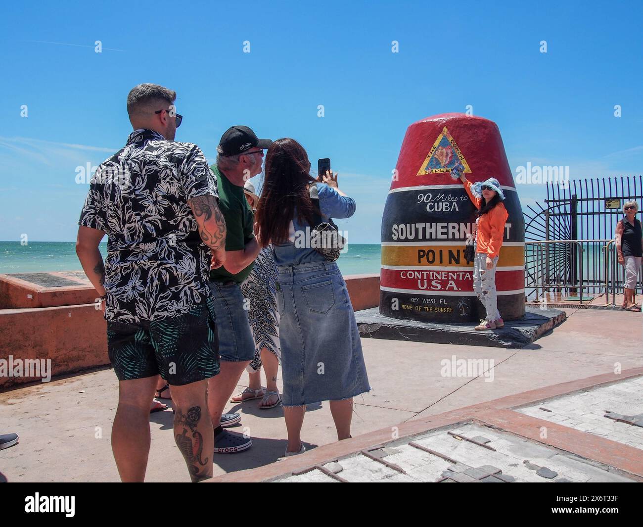 Tourist posing for photograph at the Southernmost Point buoy, Key West ...