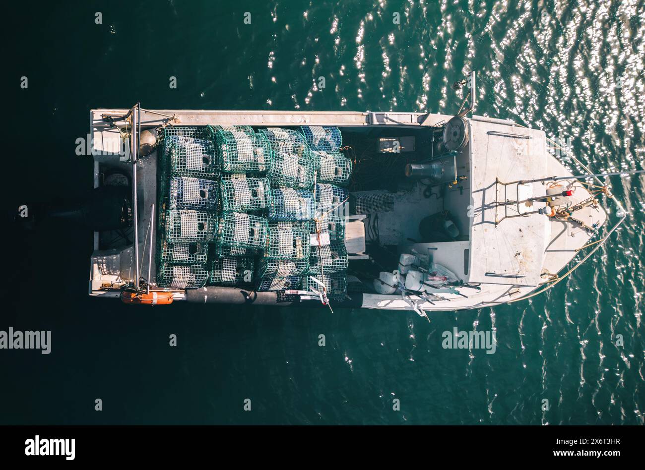 Aerial perspective of a fishing boat filled with lobster traps on calm ...