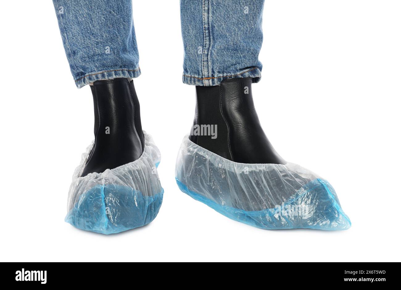 Woman wearing blue shoe covers onto her boots against white background ...