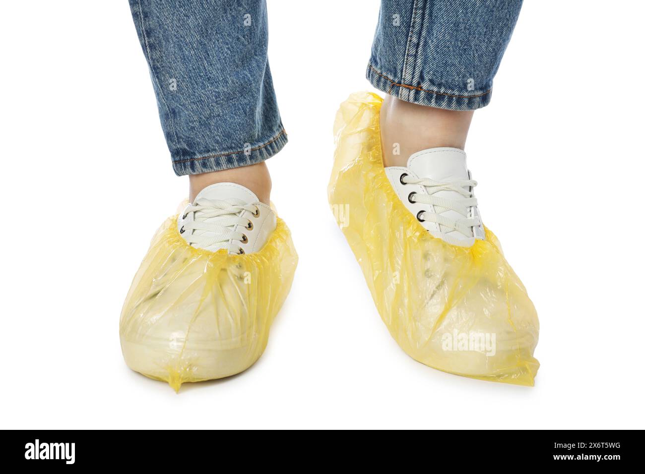 Woman wearing yellow shoe covers onto her sneakers against white ...