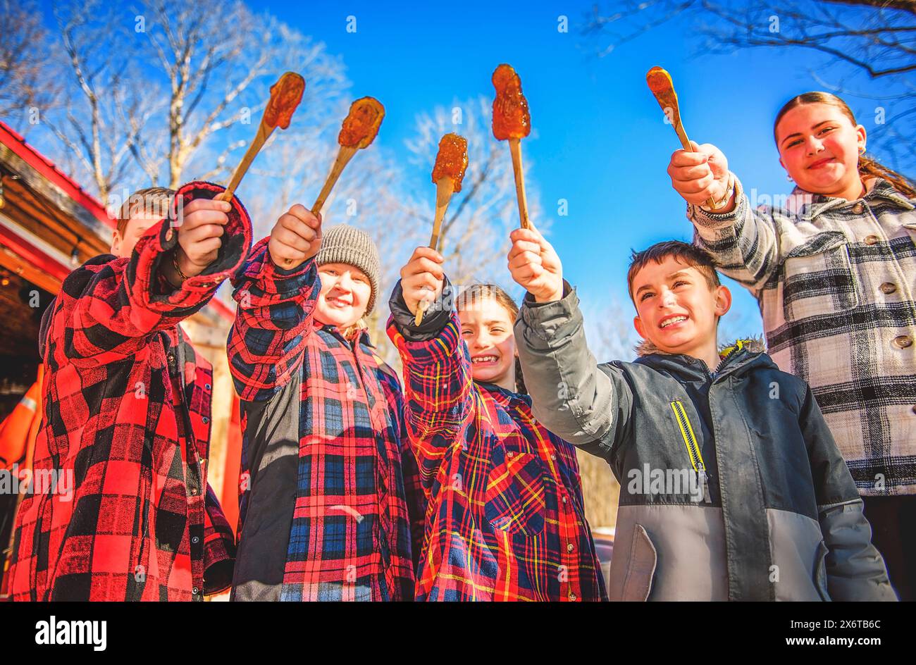 Photo showing children tasting maple syrup with wooden spoon Stock ...