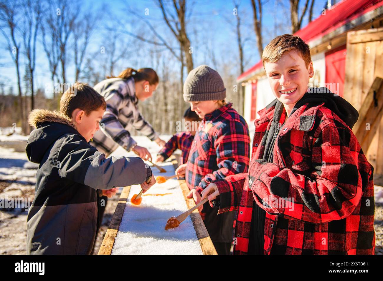 Photo showing children tasting maple syrup with wooden spoon Stock ...