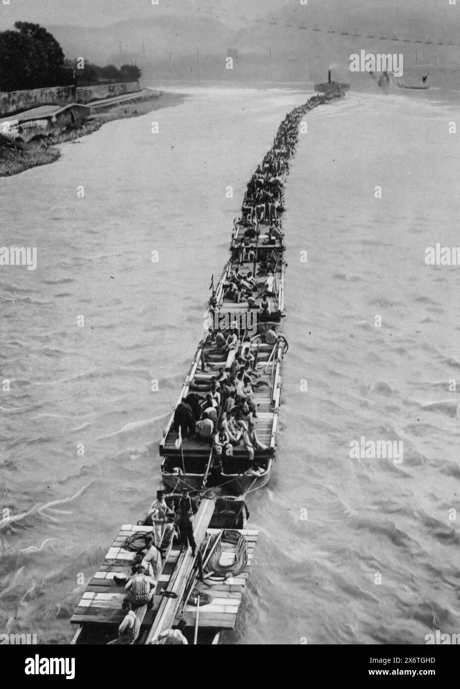 A photograph showing French engineers towing a long pontoon bridge into ...