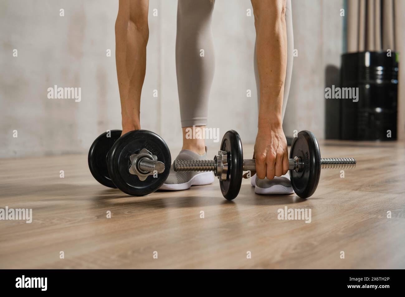 Closeup view of muscular female arms lifting dumbbells from the floor ...