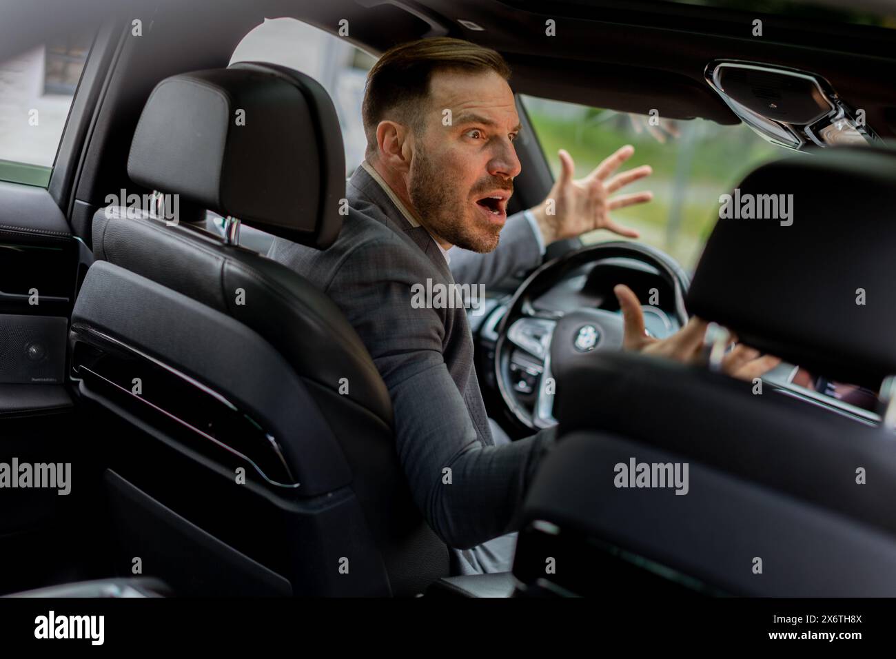 An angry man in a suit yelling while behind the wheel in gridlocked ...