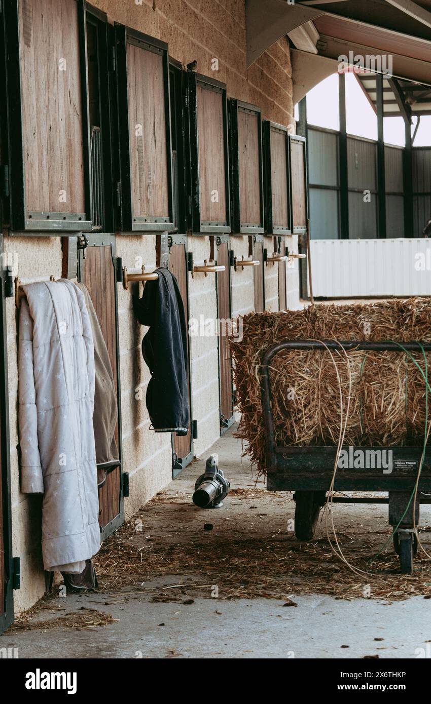 View of a rustic horse stable featuring hanging jackets and a bale of ...
