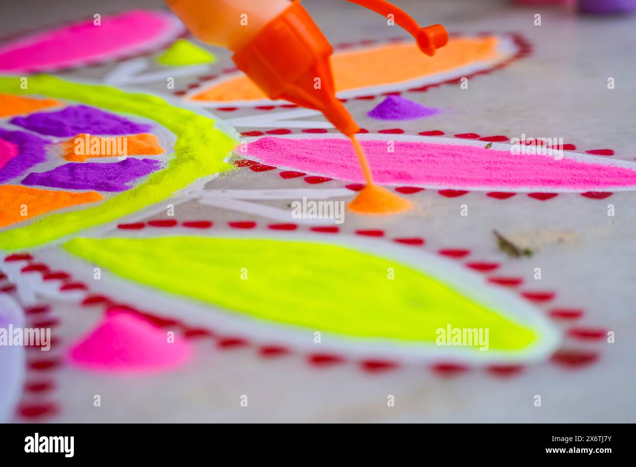 Woman using a bottle of pour a mound of orange color onto the ground to ...