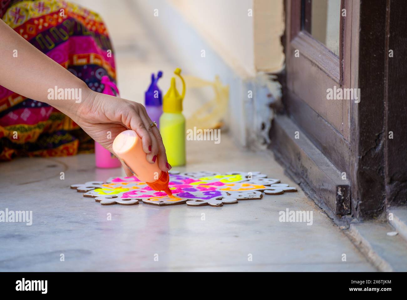 Indian woman in traditional indian clothing using bottles of color ...