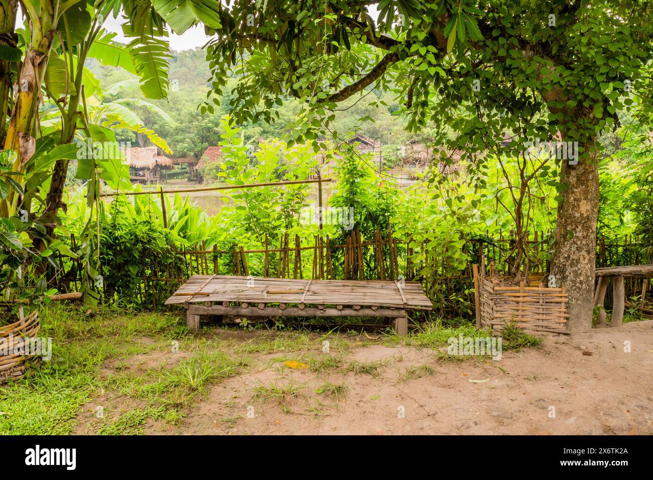 Wooden table in front of bamboo fence in small southeast Asian farming ...