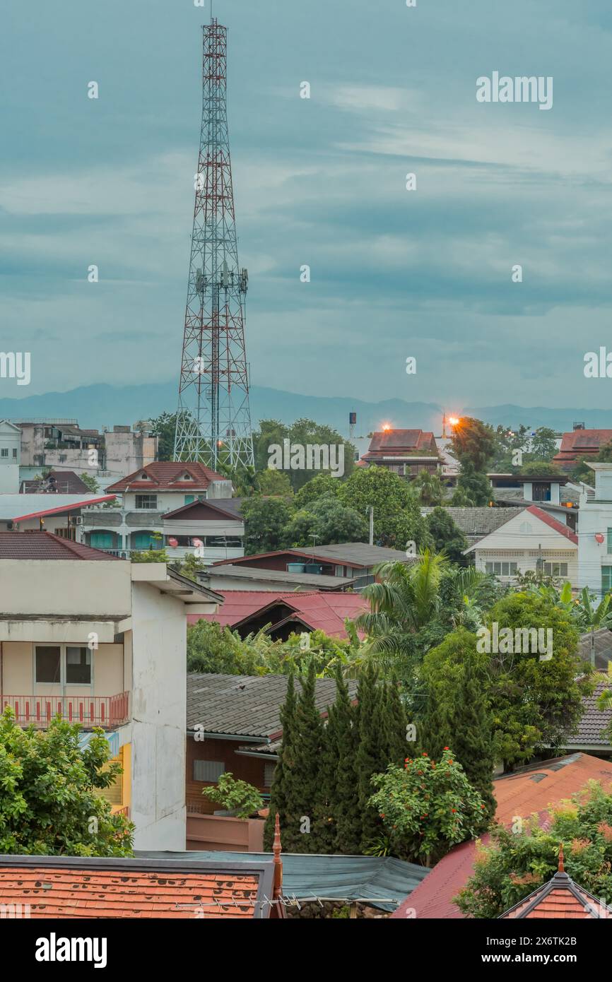 Communication tower above rooftops under cloudy morning sky. Taken from ...