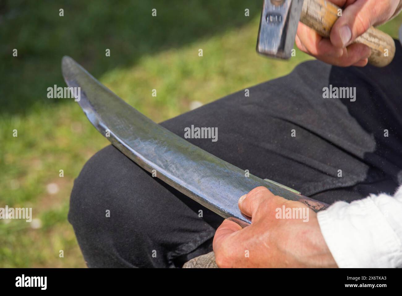 Man peening a scythe blade using a jig and a hammer to sharpen it Stock ...