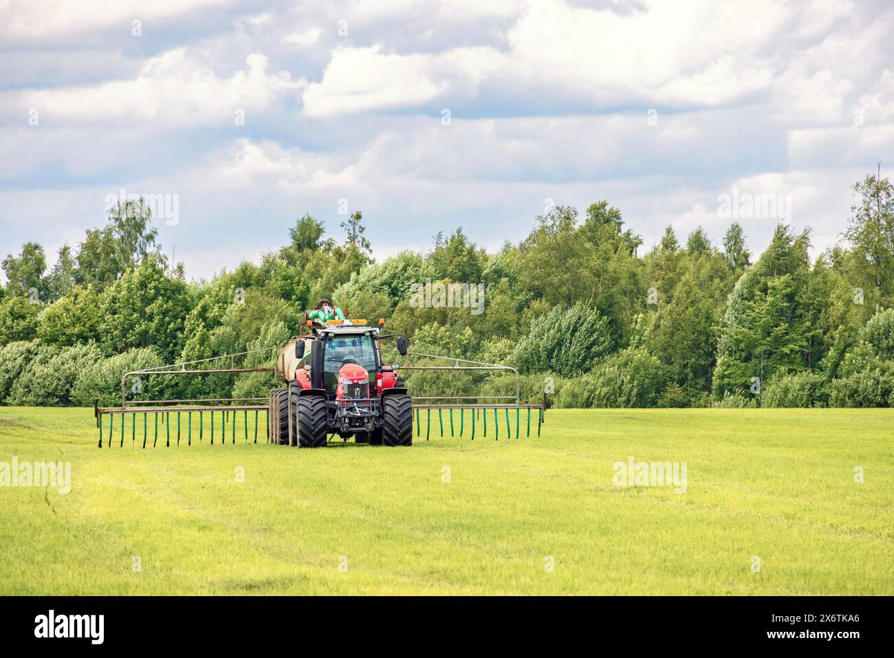 Tractor fertilizing a green field in the countryside Stock Photo - Alamy