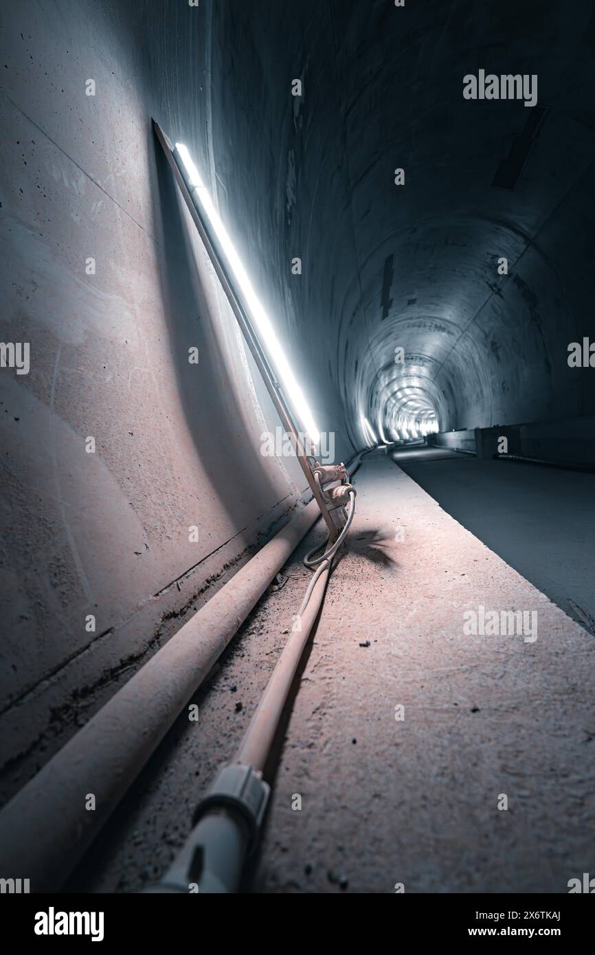 An urban tunnel with industrial pipes and lighting, concrete walls and ...