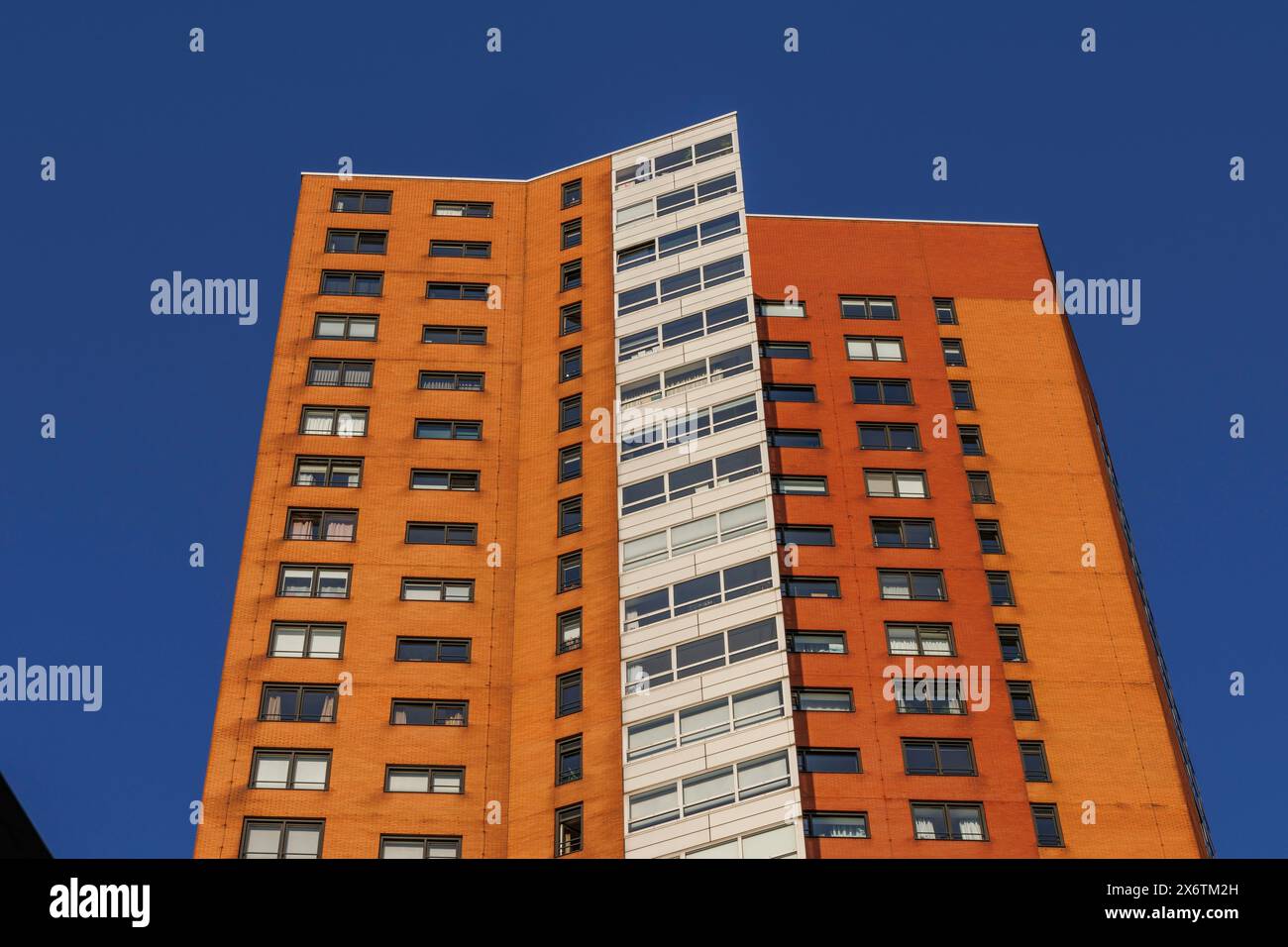 Modern high-rise brick building with many glass windows under a clear ...