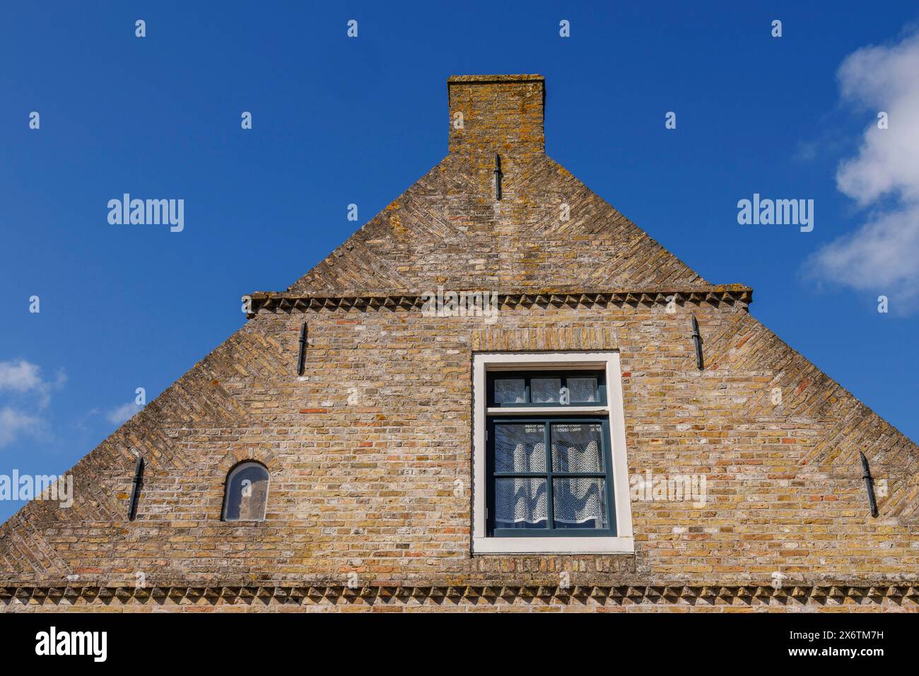 Close-up of a rustic brick house gable with a window under a bright ...