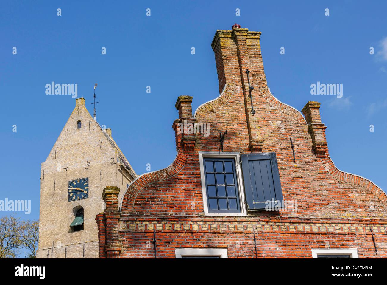A bell tower and a brick house with a tiled roof and windows under a ...