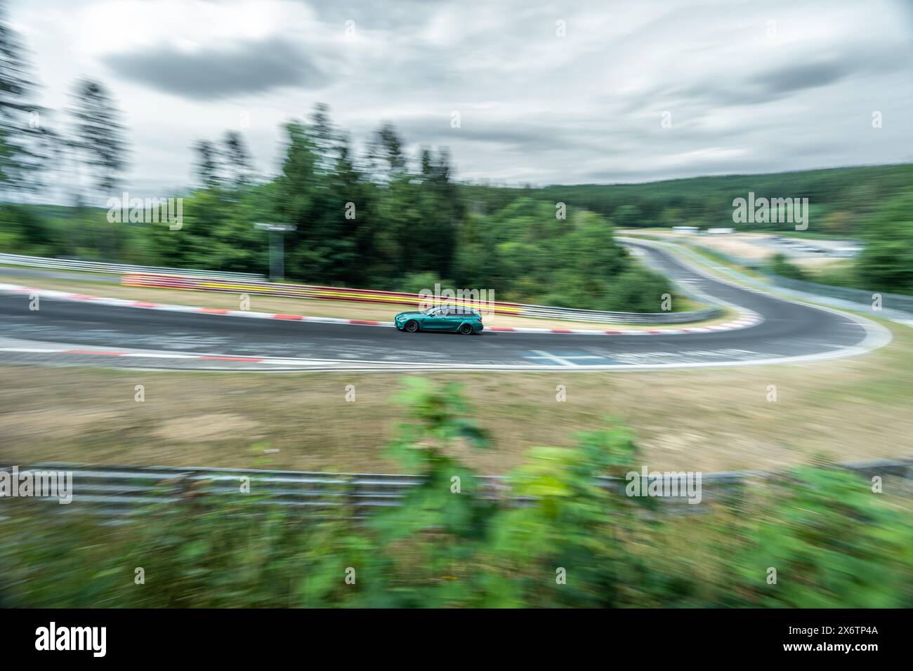 A car races around a racetrack with a bend with visible motion blur ...
