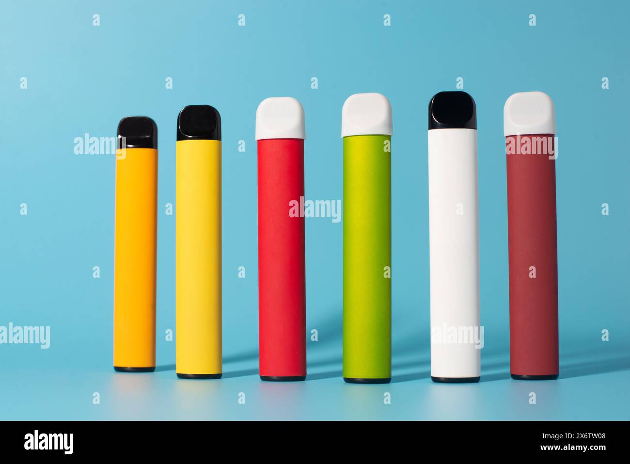 Set of colorful disposable electronic cigarettes with shadows on a blue ...