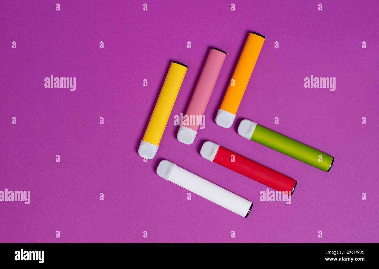 Colorful disposable electronic cigarettes on a purple background. The ...