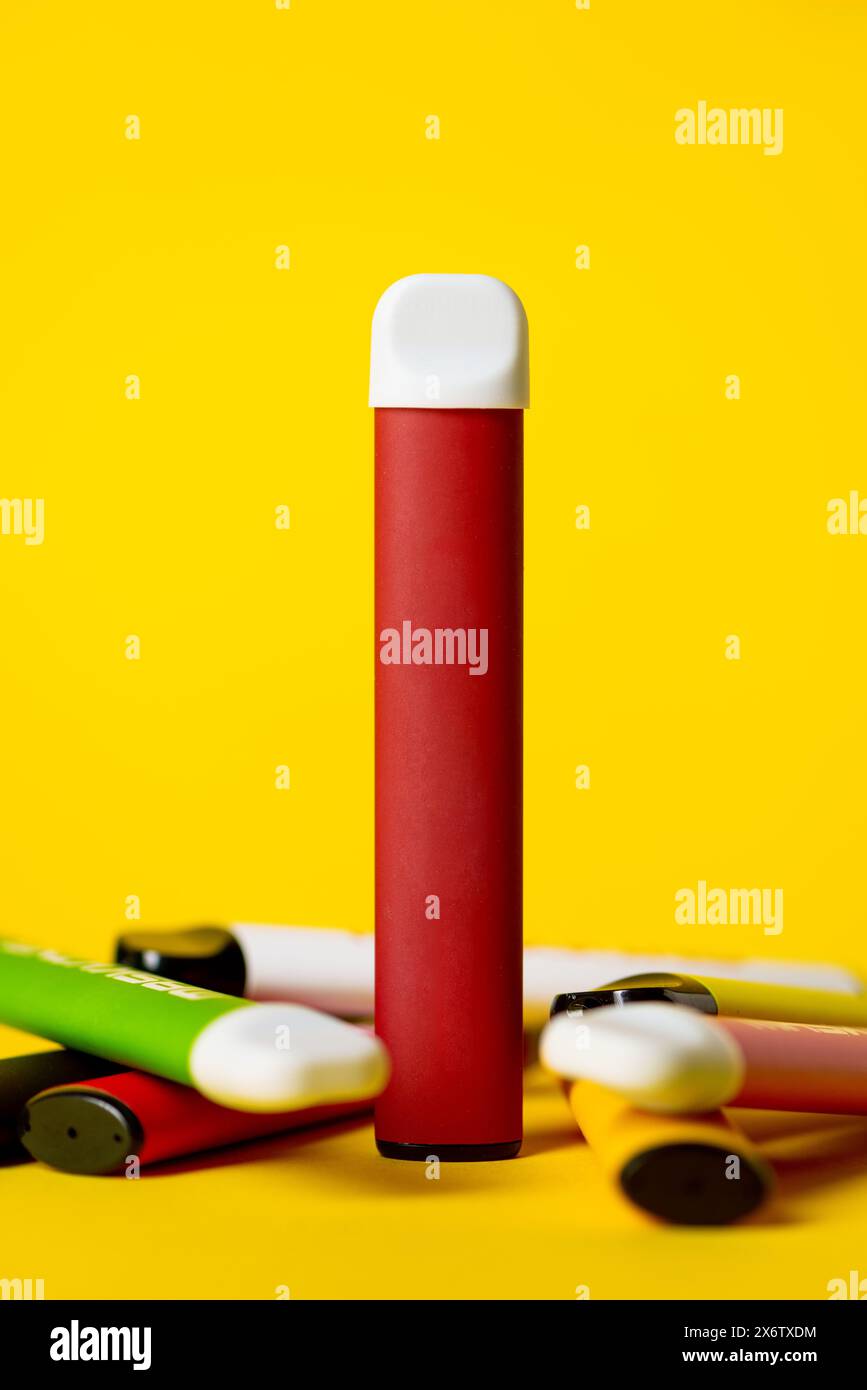 Colorful disposable electronic cigarettes on a yellow background. The ...