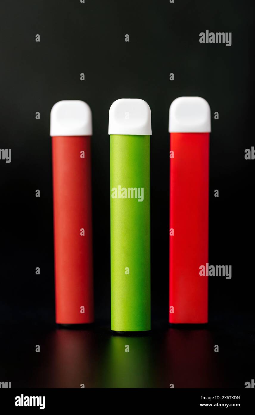 Colorful disposable electronic cigarettes on a black background. The ...