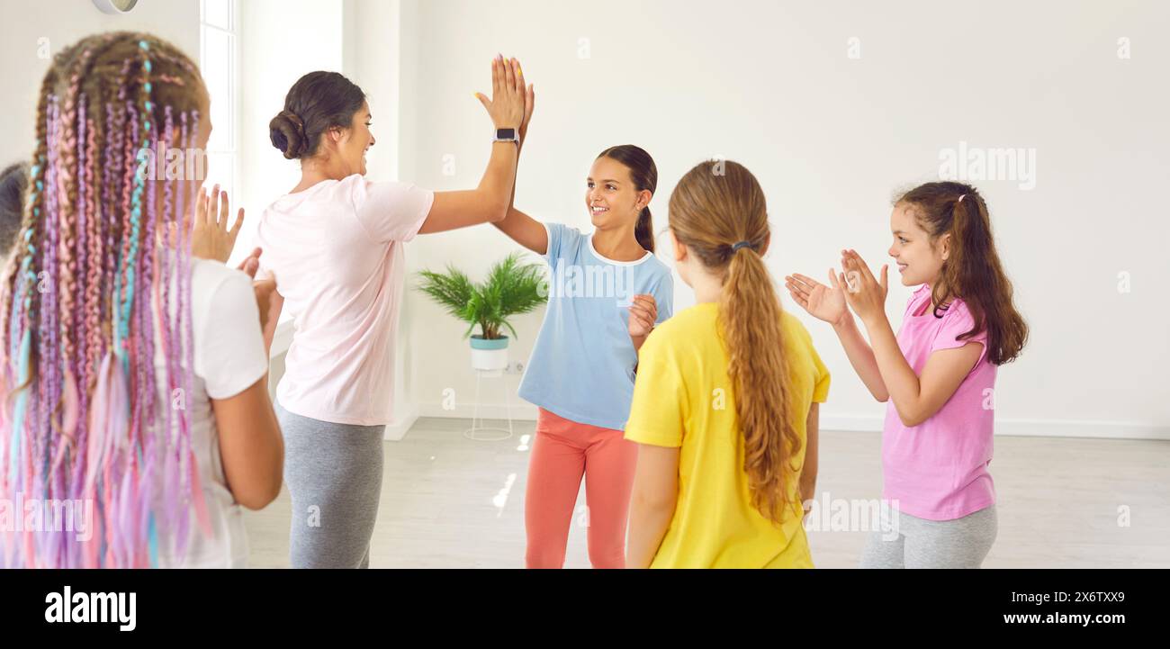 Friendly female choreographer gives high five to her students after ...
