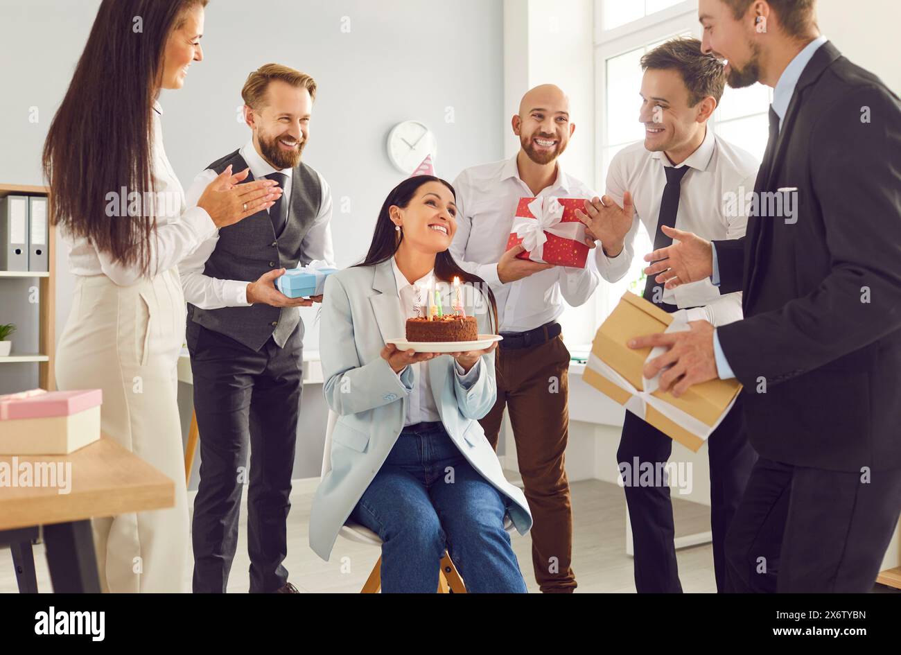 People congratulating colleague with birthday giving her cake and gift ...