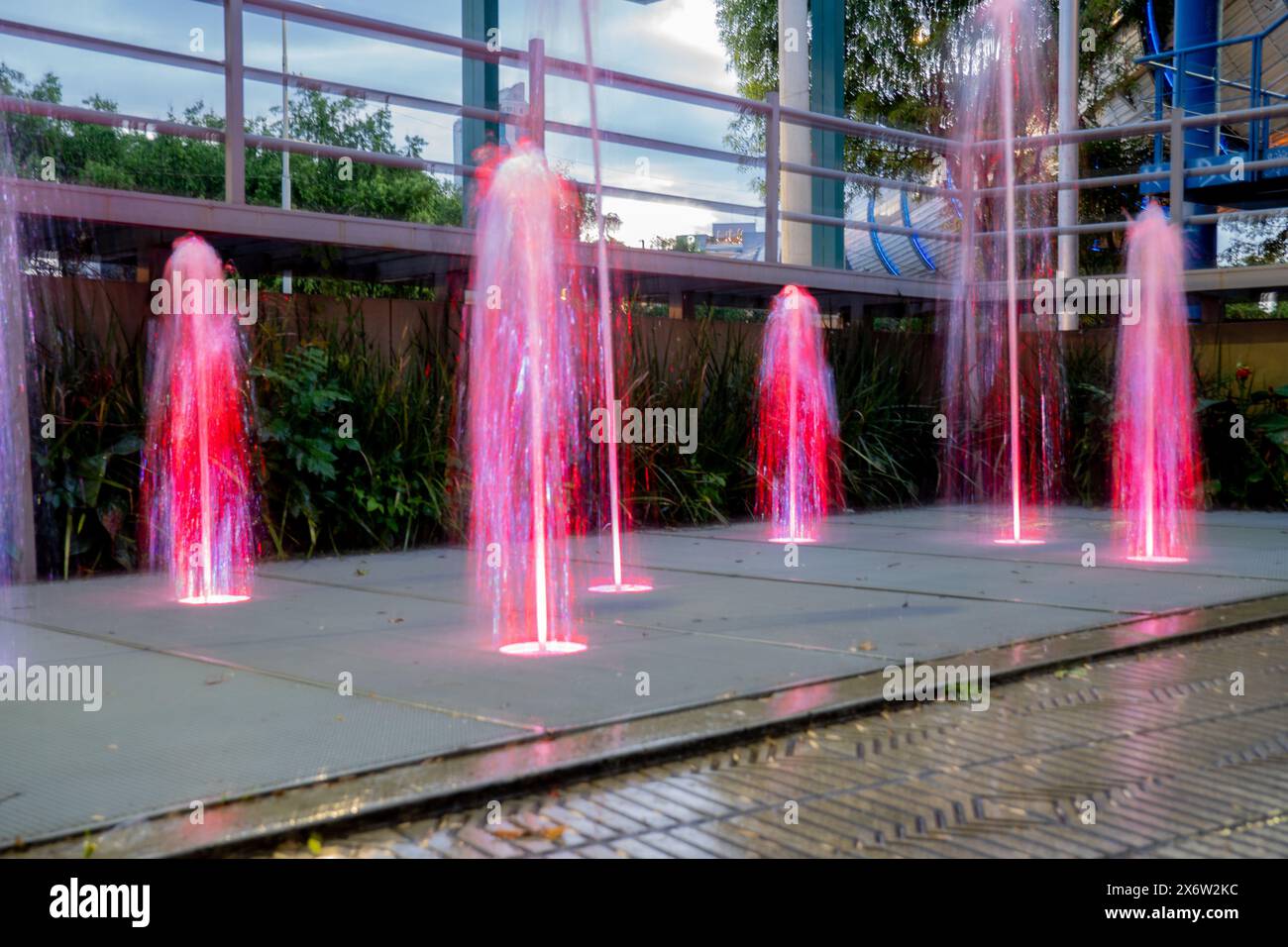 Jet of water from a splashing fountain, colorful lighting. Long ...