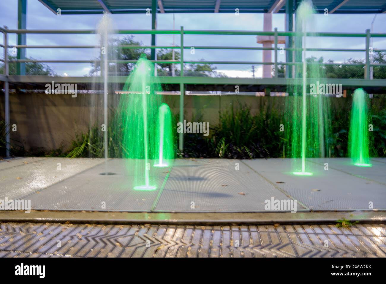 Jet of water from a splashing fountain, colorful lighting. Long ...