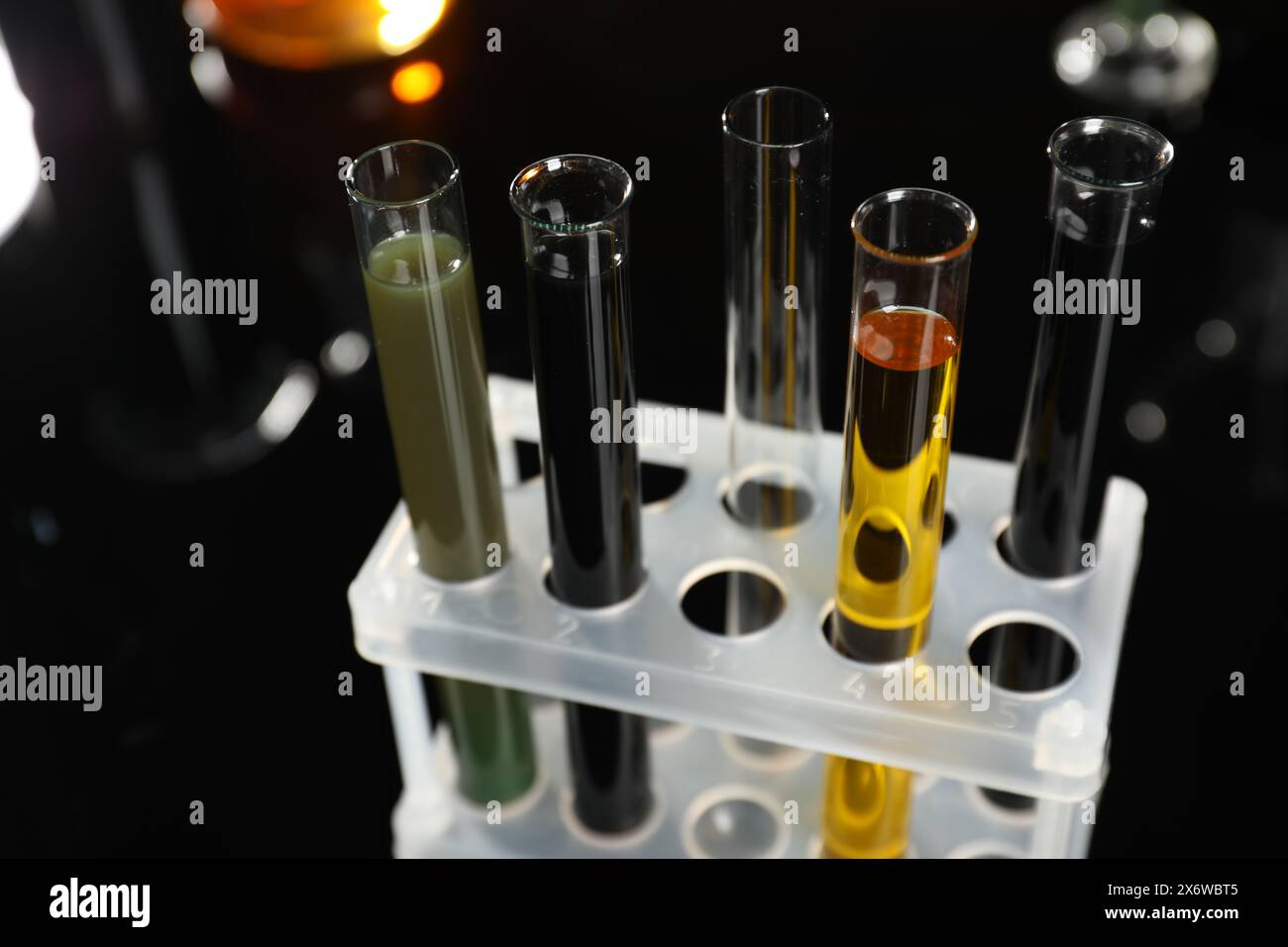 Test tubes with different types of oil on black background, closeup ...