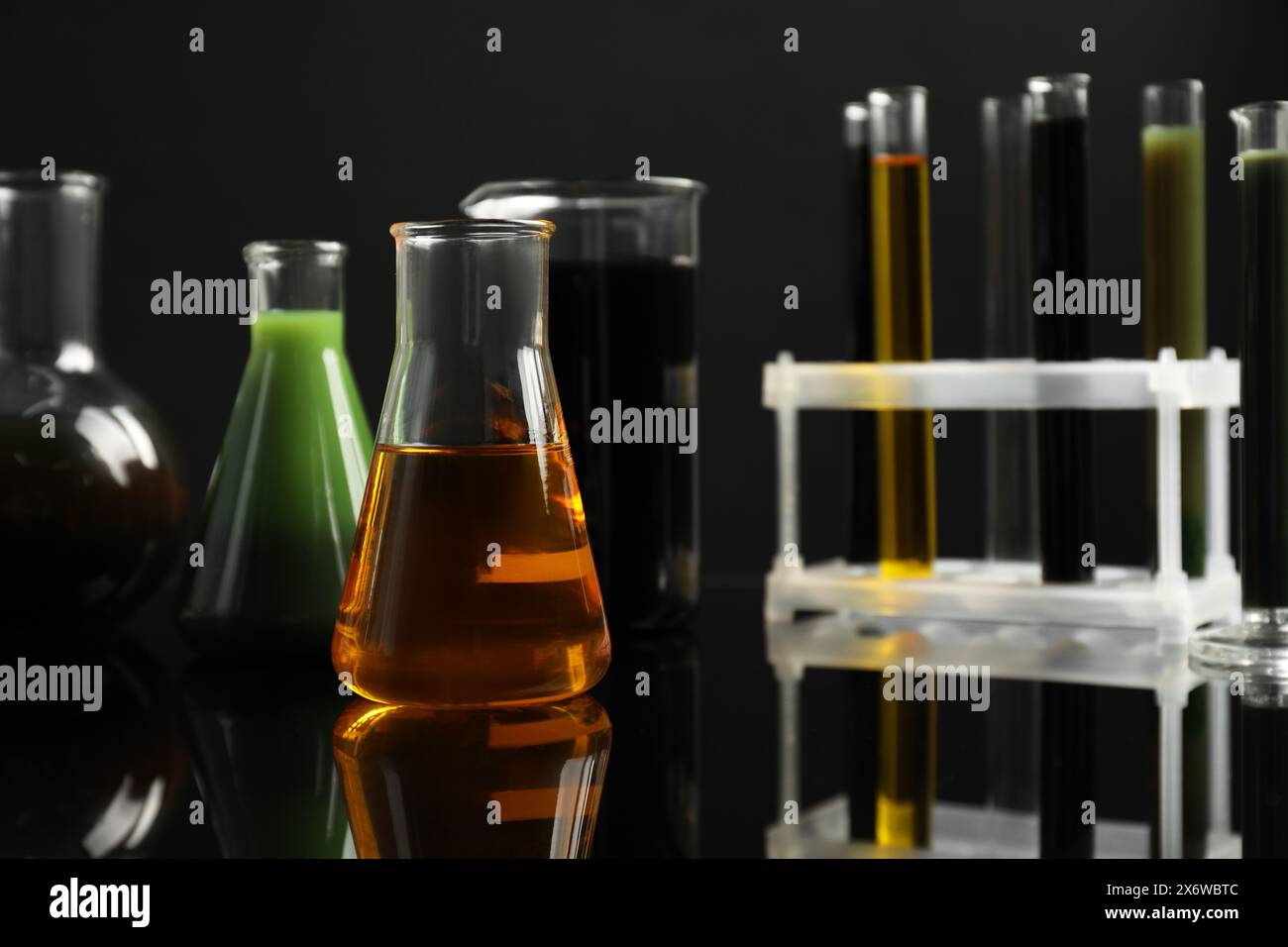 Laboratory glassware with different types of oil on black background ...