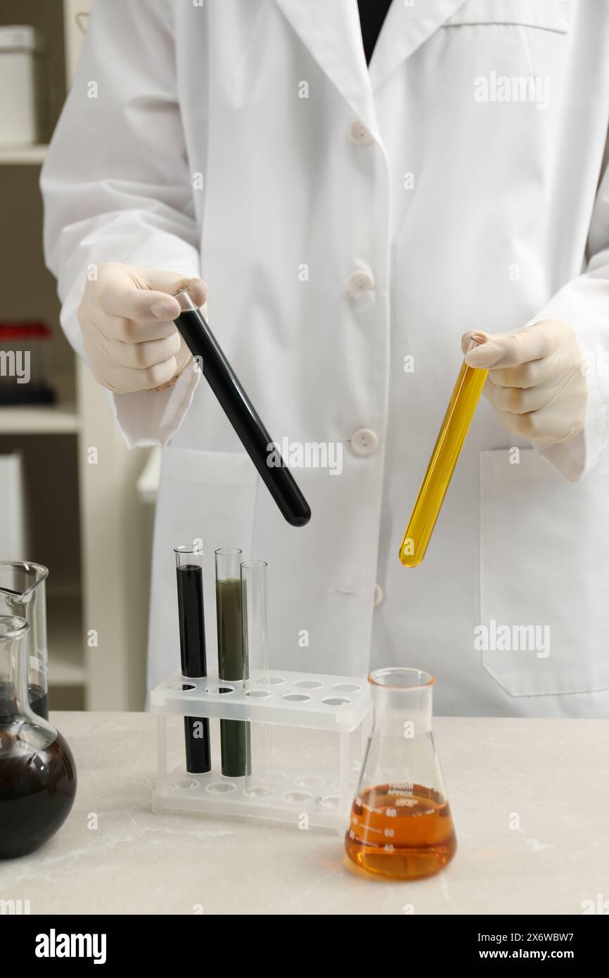 Laboratory worker holding test tubes with different types of crude oil ...