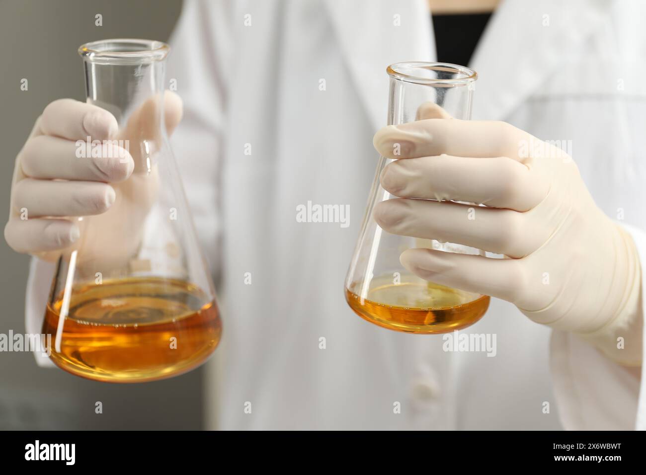 Laboratory worker holding flasks with orange crude oil, closeup Stock ...