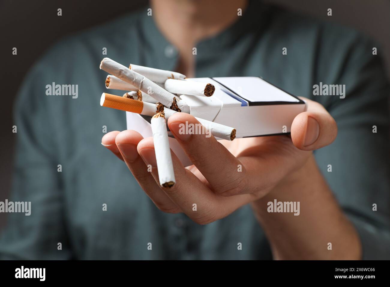 Stop smoking. Man holding pack with broken cigarettes on grey ...