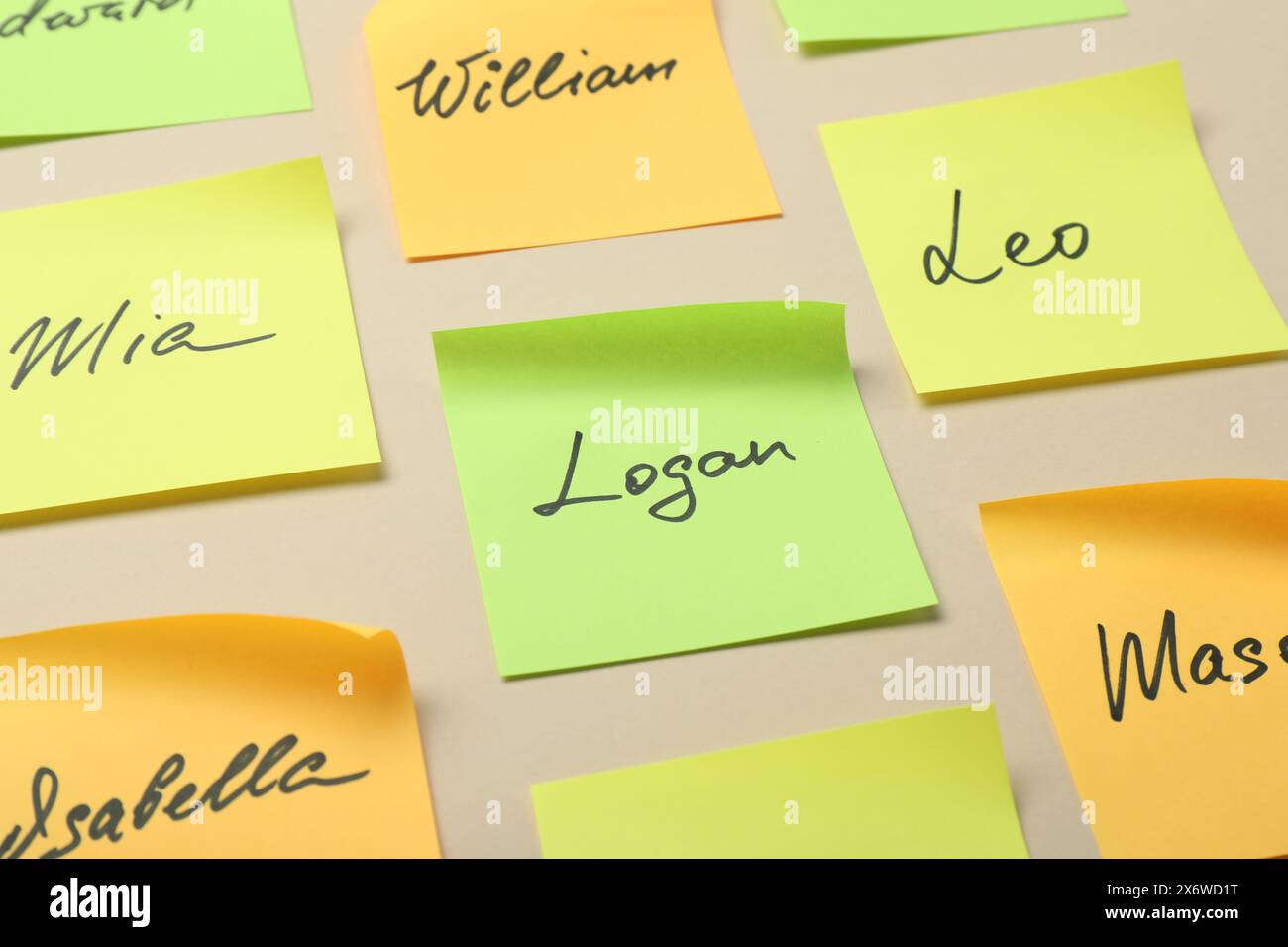 Paper stickers with different names on beige background, closeup ...