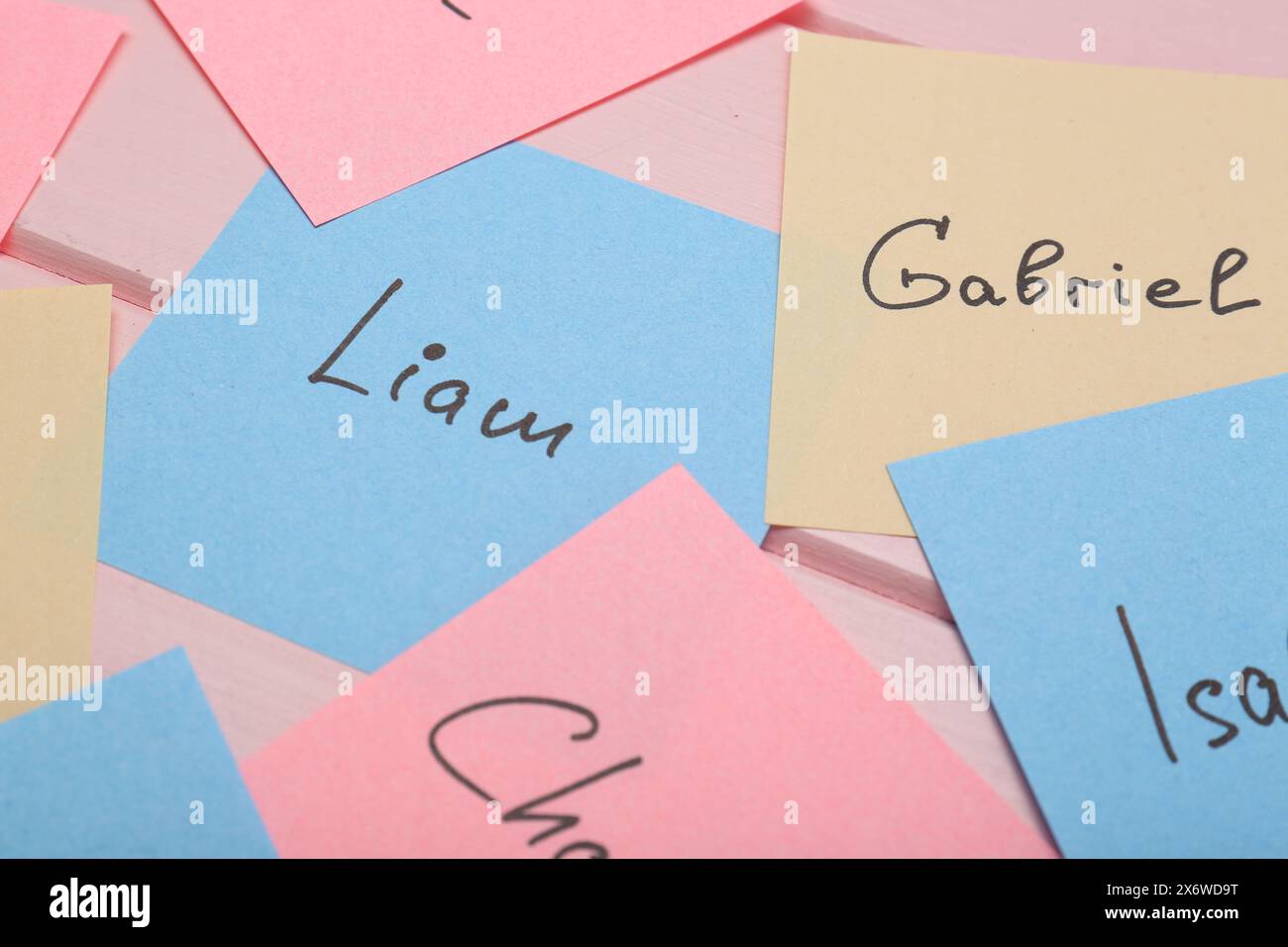 Paper stickers with different names on pink wooden table, closeup ...