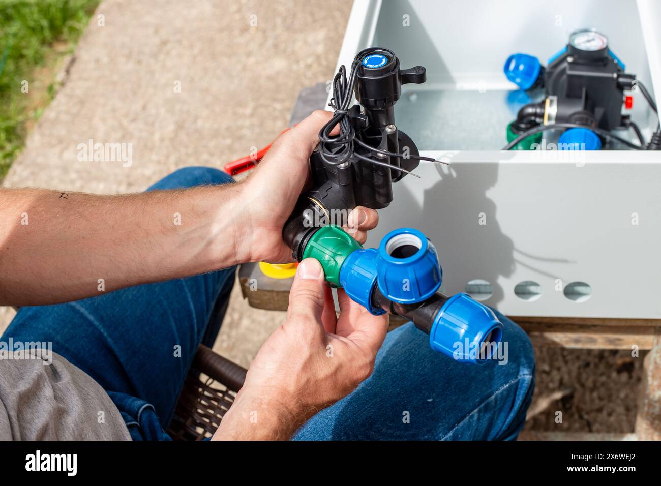 The master installs drip irrigation for the garden. A man tries on ...