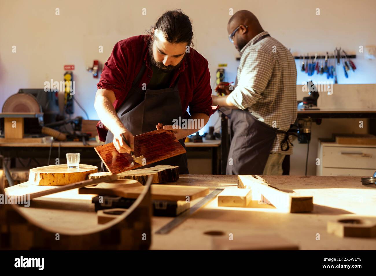 Carpenter brushing varnish on wood to build up protective layer with ...