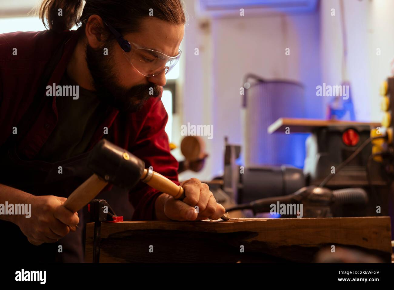 Man shaping raw timber using chisel and hammer in carpentry shop ...