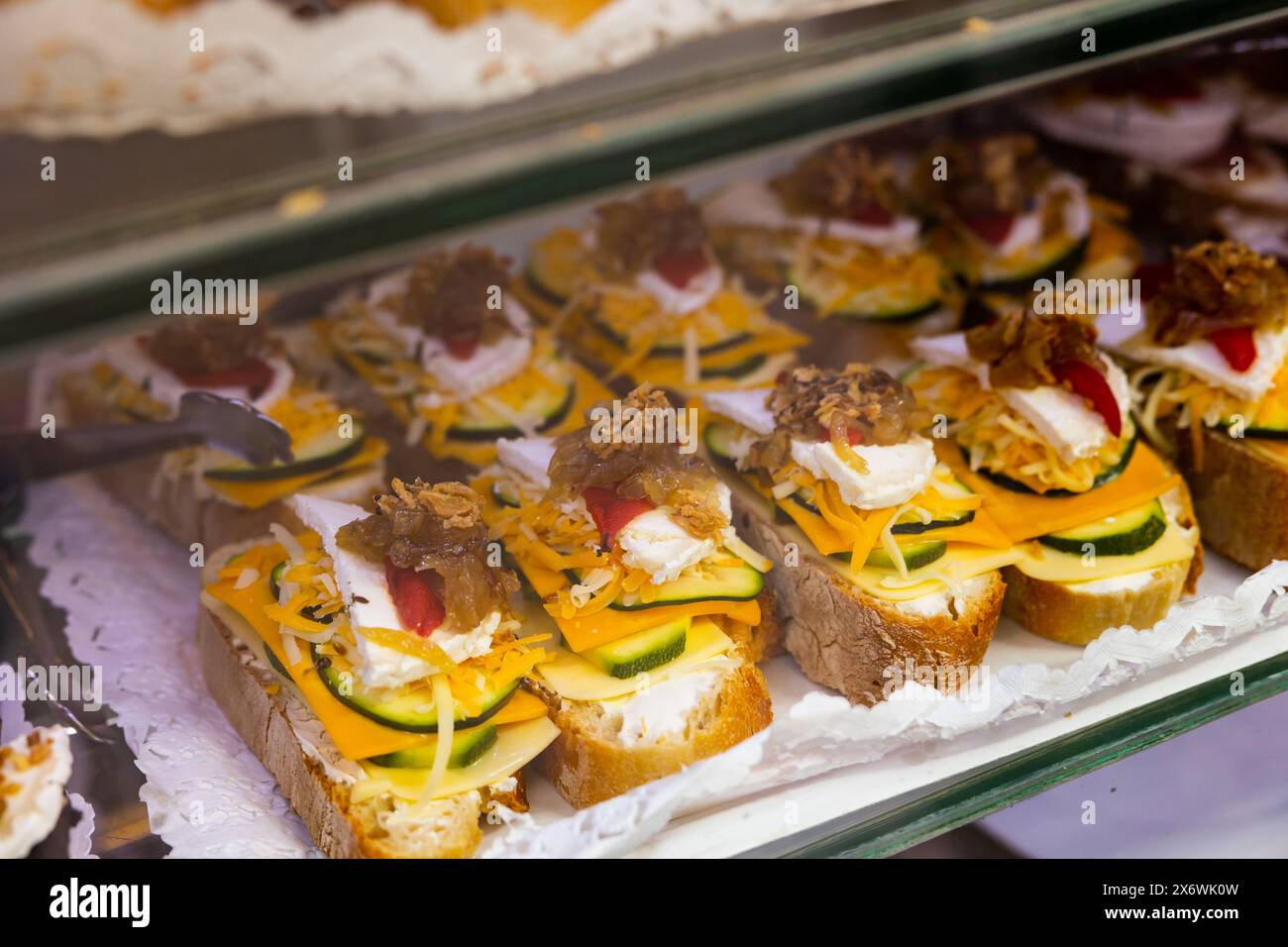 Pinchos with cheese, cucumber, pepper and caramelized onions on display ...