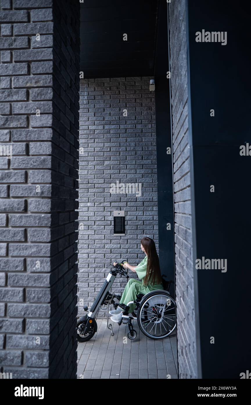 A woman in a wheelchair with an assistive device for manual control ...