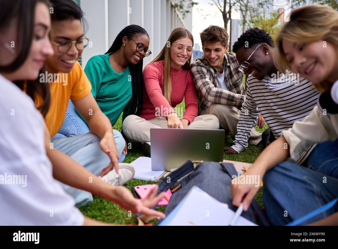 Group of young international students sitting on the grass outside the ...